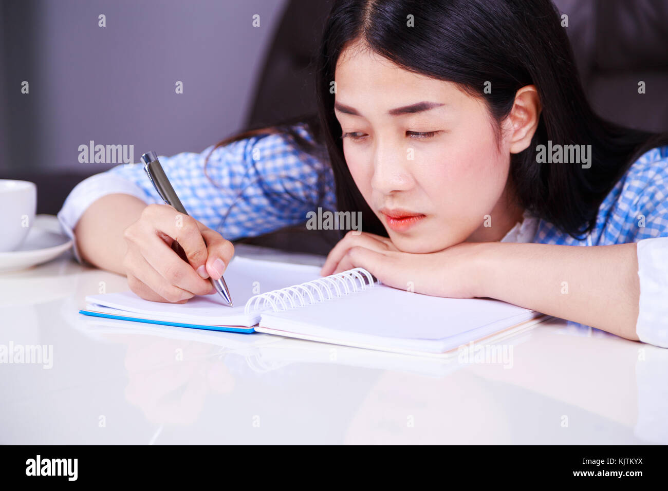 stressed young business woman sitting at her desk and writes a note on ...