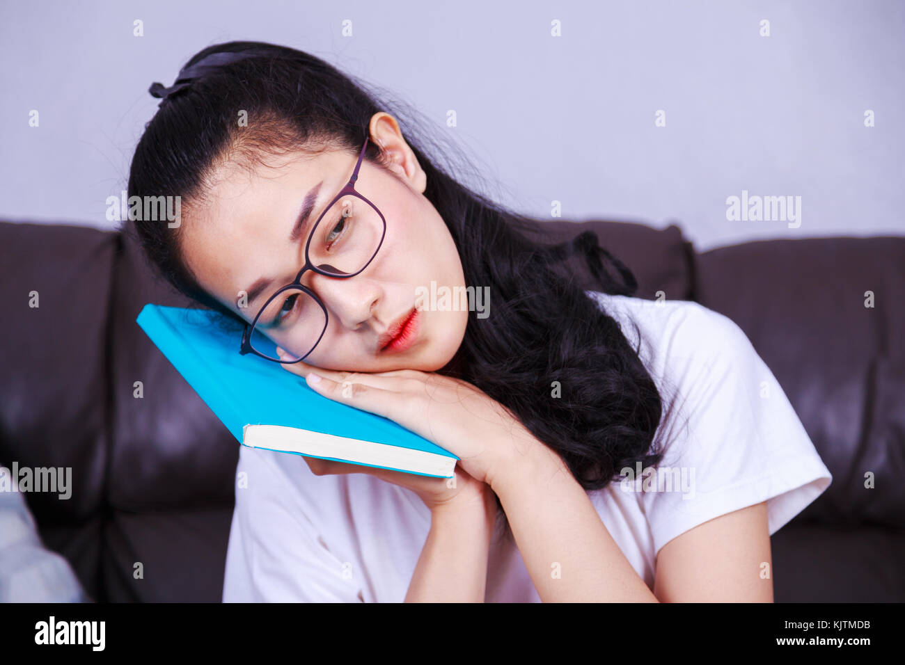 sleepy woman and reading boring book on sofa at home Stock Photo - Alamy