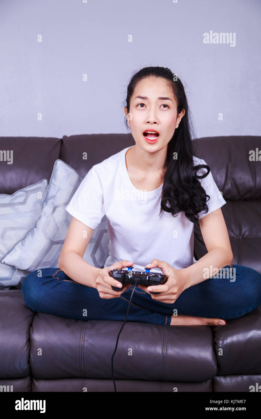woman using joystick controller playing video game on sofa in living ...