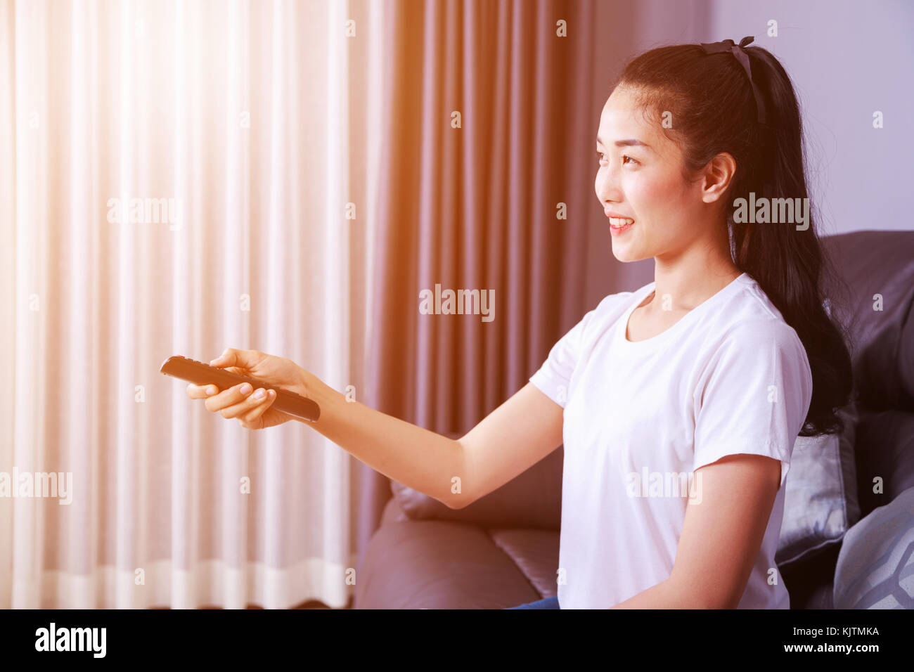woman with tv remote control on sofa in living room at home Stock Photo ...