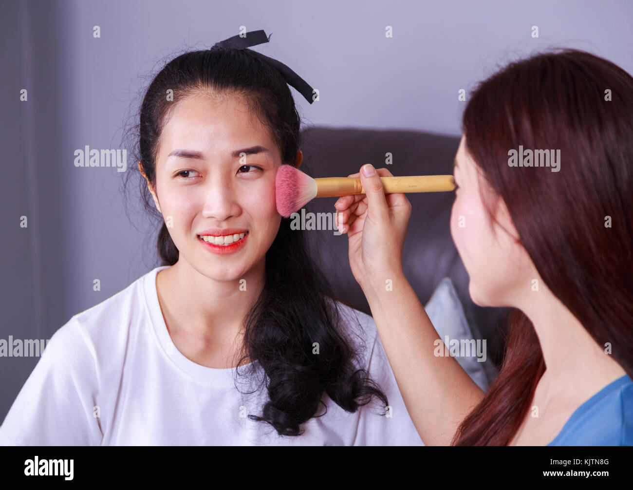 young woman using brush makeup on face her friend Stock Photo - Alamy