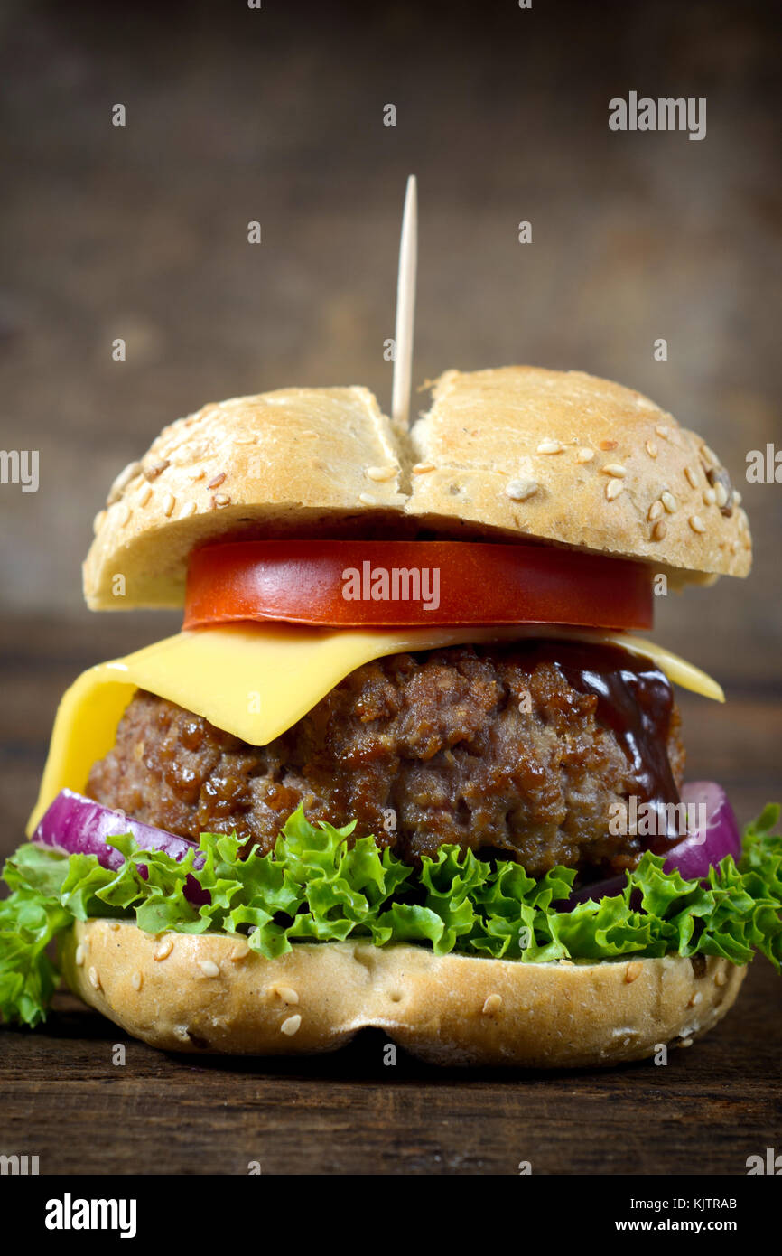 Single juicy cheeseburger on the wooden table Stock Photo - Alamy