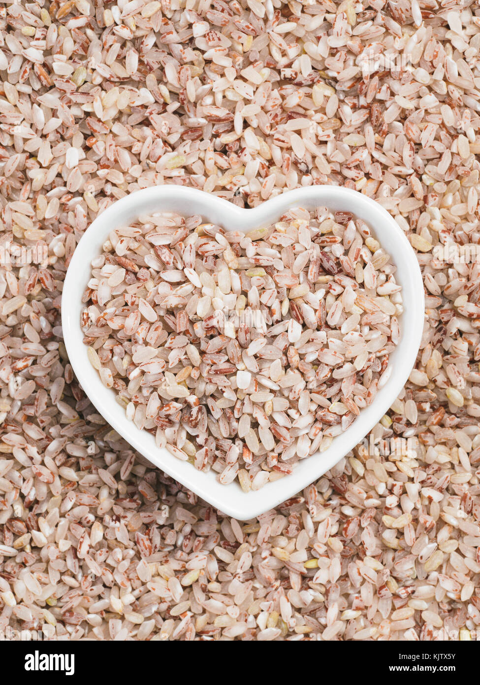 Red rice in heart-shaped bowl on rice background Stock Photo - Alamy