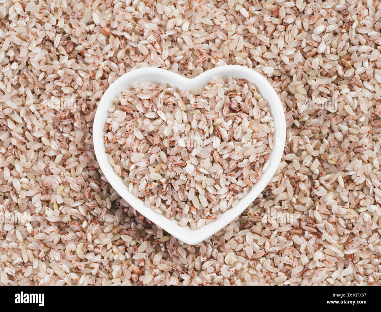 Red rice in heart-shaped bowl on rice background Stock Photo - Alamy