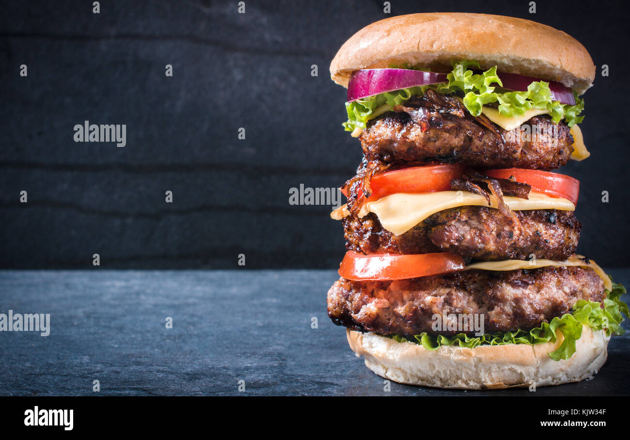 Triple American burger with cheese and grilled onions,selective focus ...