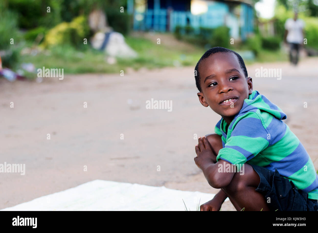 cheerful child crouching beside the road looking at the camera Stock ...