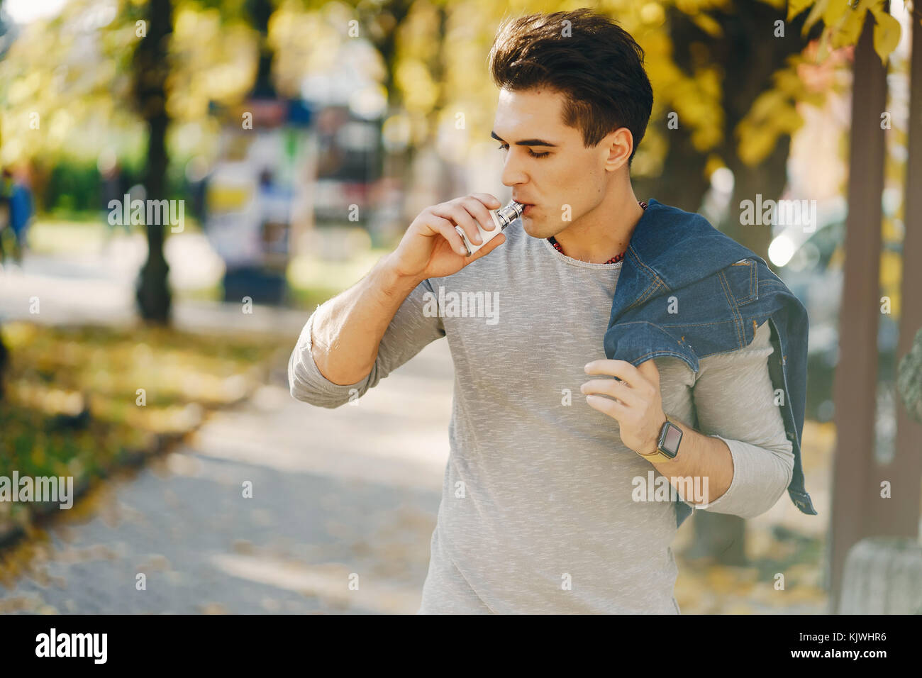 stylish man walking through the city smoking an e-cigarette Stock Photo ...