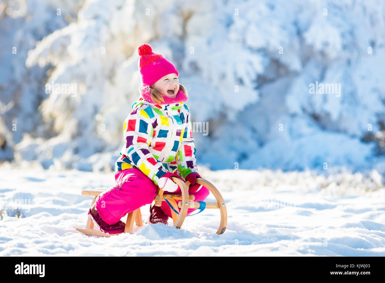 Little girl enjoying a sleigh ride. Child sledding. Toddler kid riding ...