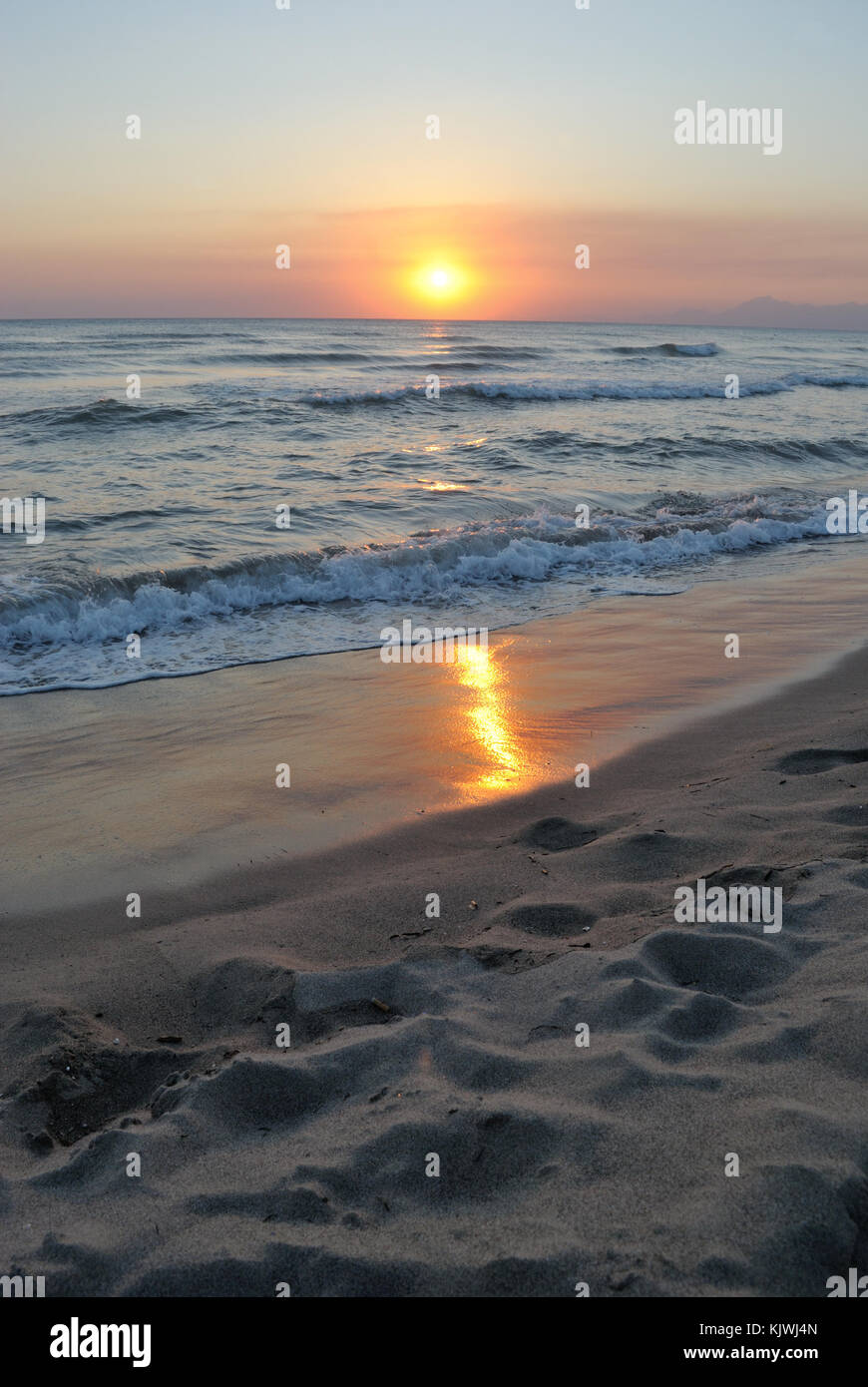 romantic sunset reflected on the beach, vertical Stock Photo - Alamy