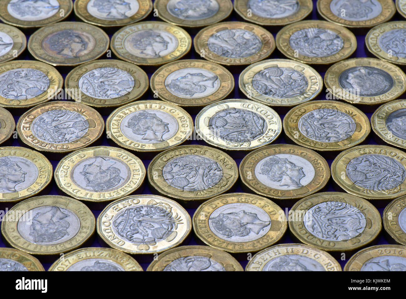 A number of one pound coins lying flat on a table or background making ...