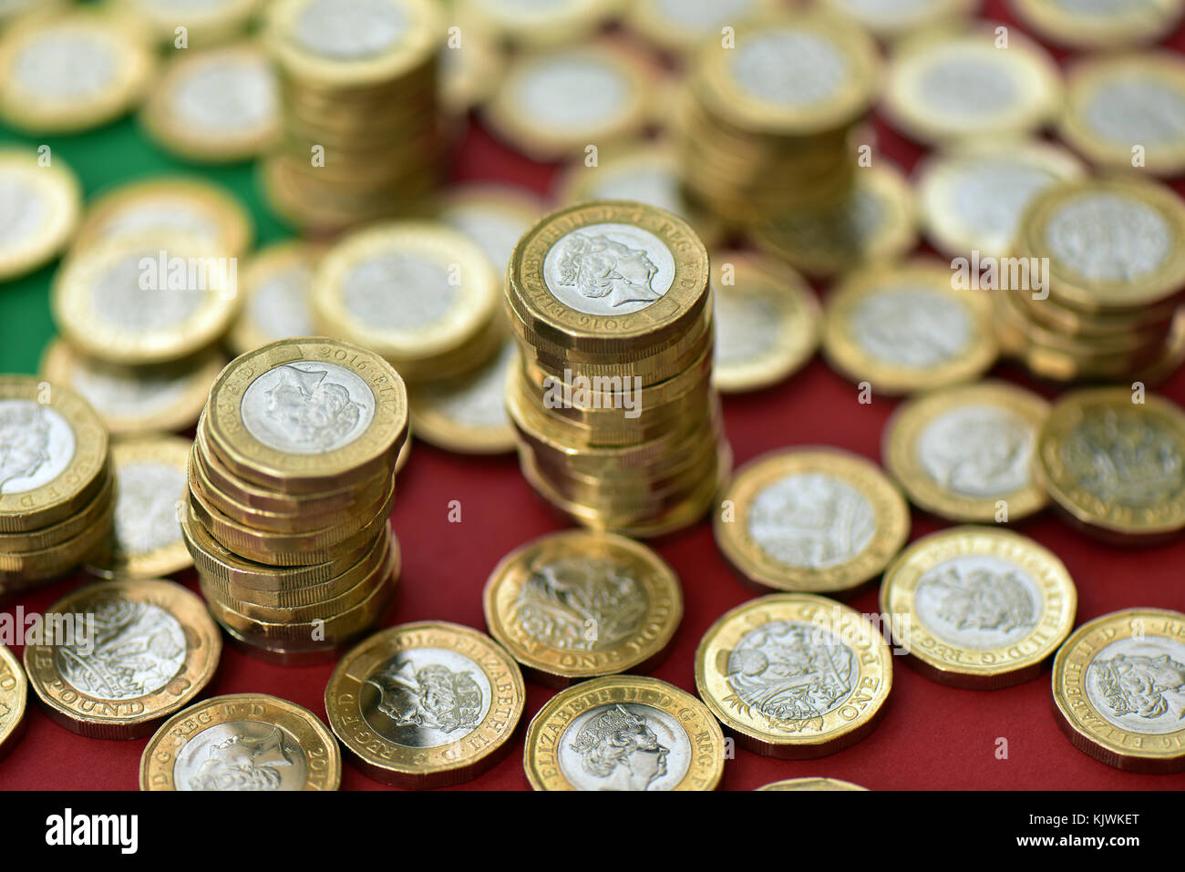 A large number of one pound coins on a red and green background. New ...