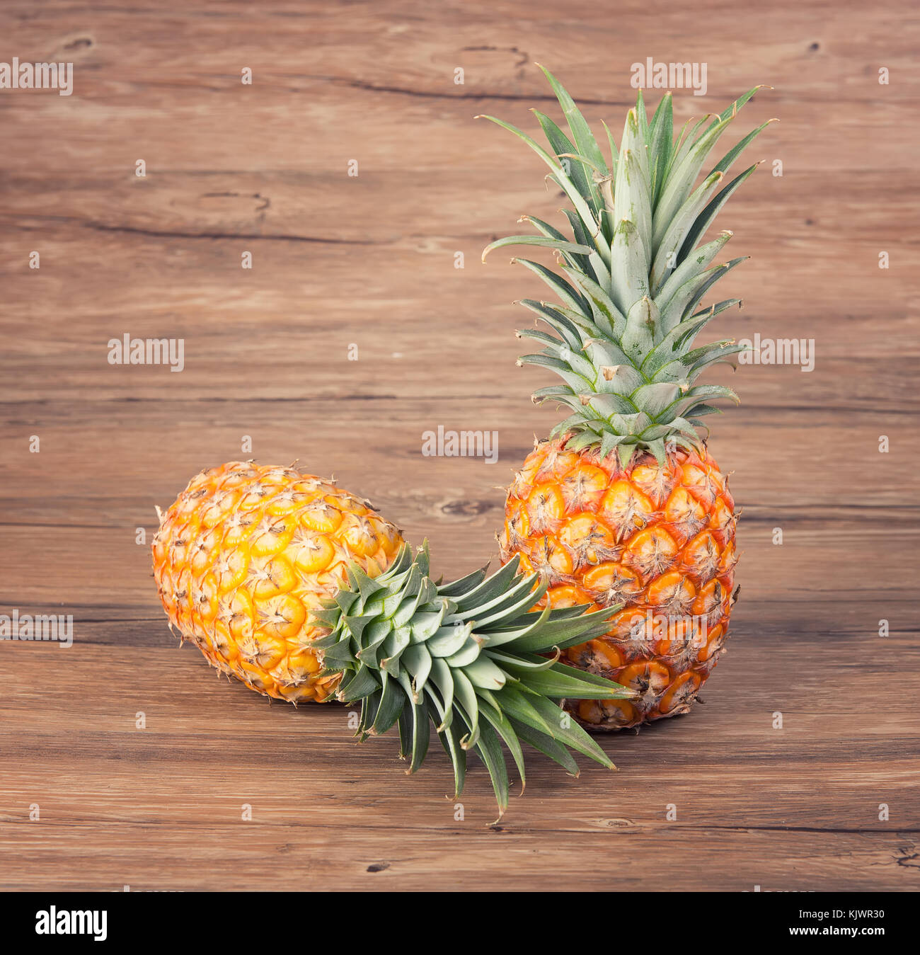 two pineapples on wooden grunge background Stock Photo - Alamy