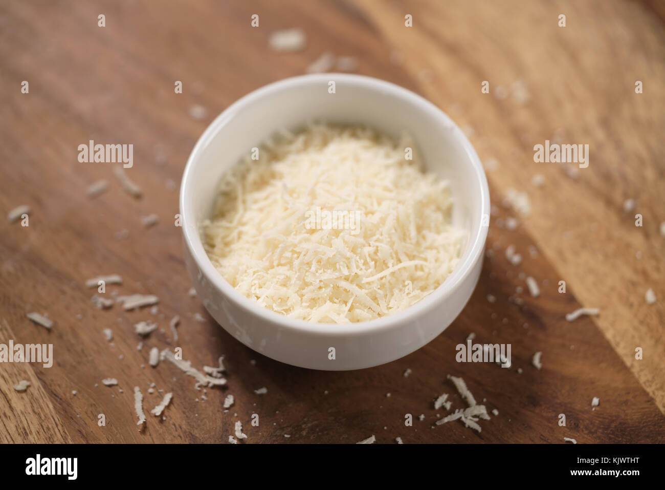 grated aged italian parmesan cheese in white bowl on table Stock Photo ...