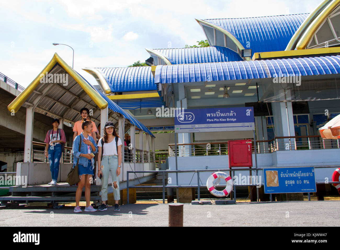 People wait for a river boat at Phra Pin Klao dock on the Chao Phraya ...