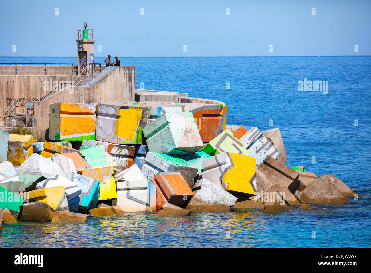 Colourful painted concrete wave breakers at the entrance to Llanes ...