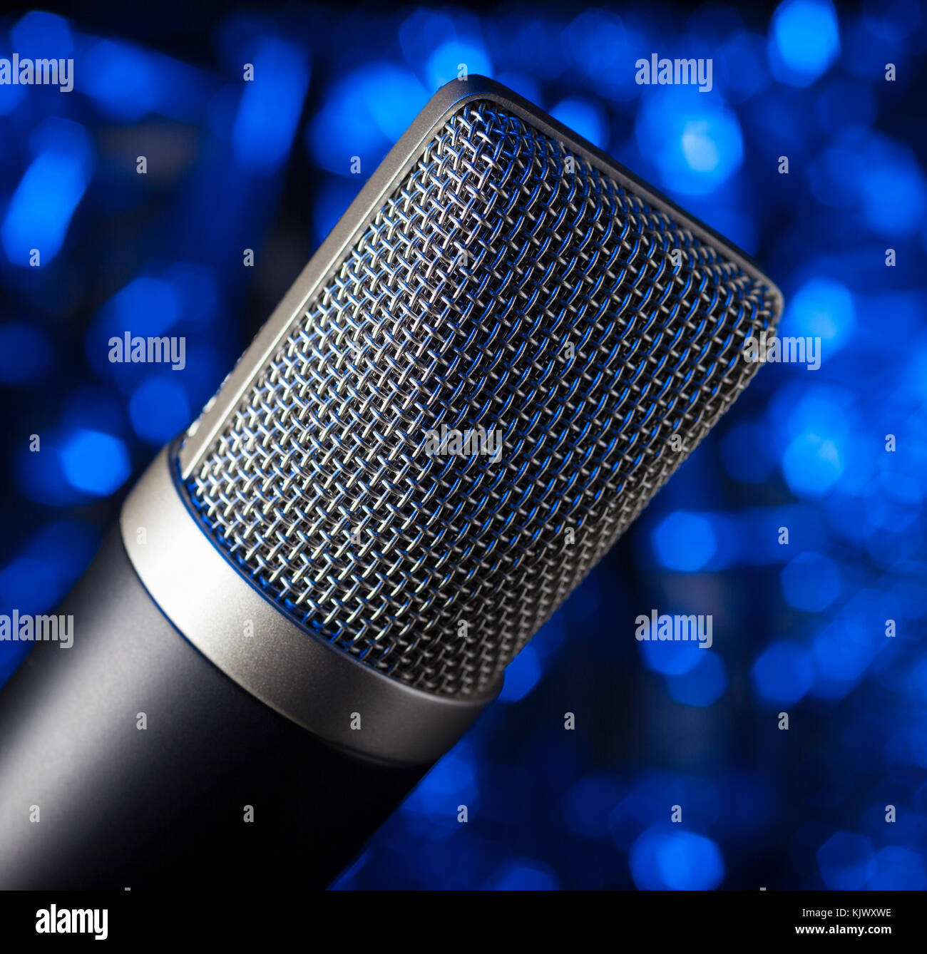 Metal covered microphone that has a blue background Stock Photo - Alamy