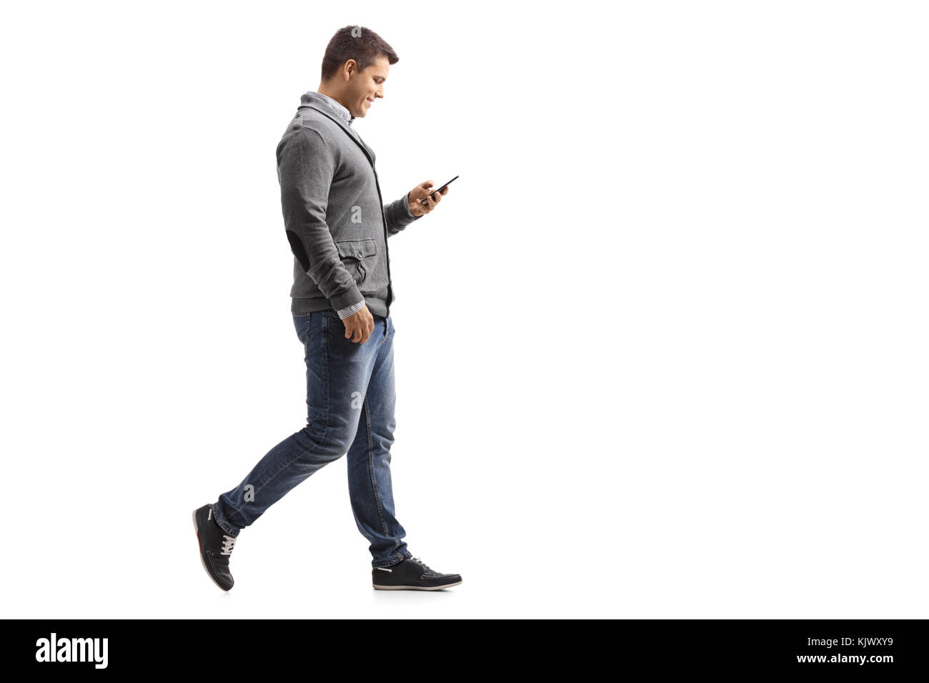 Full length profile shot of a young man walking and using a phone ...
