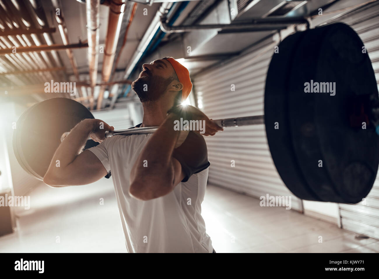 Young muscular man doing high pull exercise with barbell on cross ...