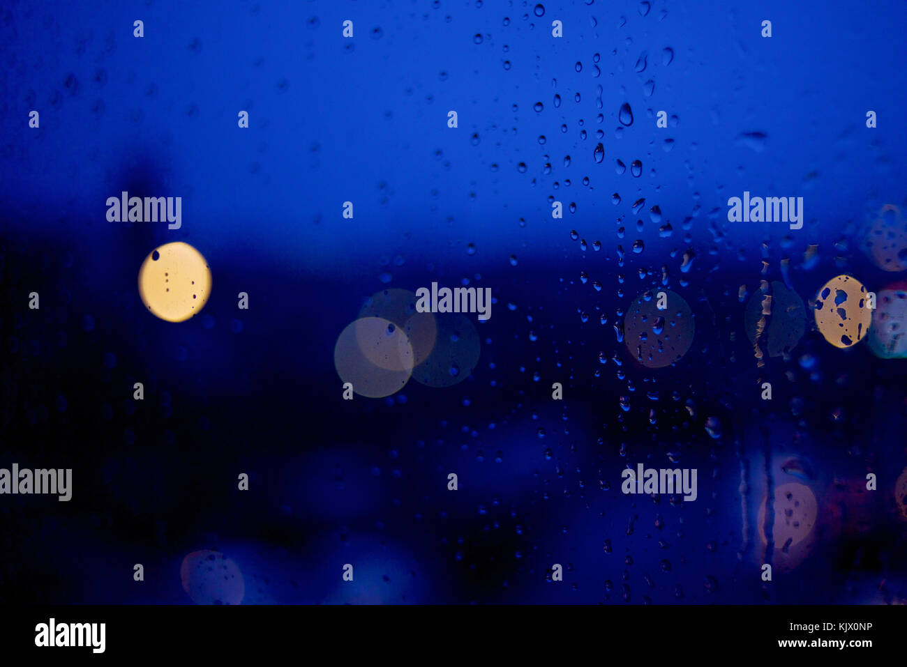 View through a window at night with raindrops and bokeh effect on ...
