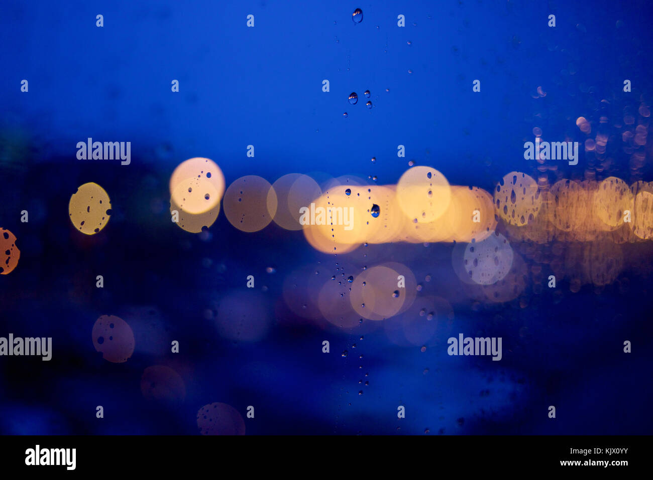 View through a window at night with raindrops and bokeh effect on ...