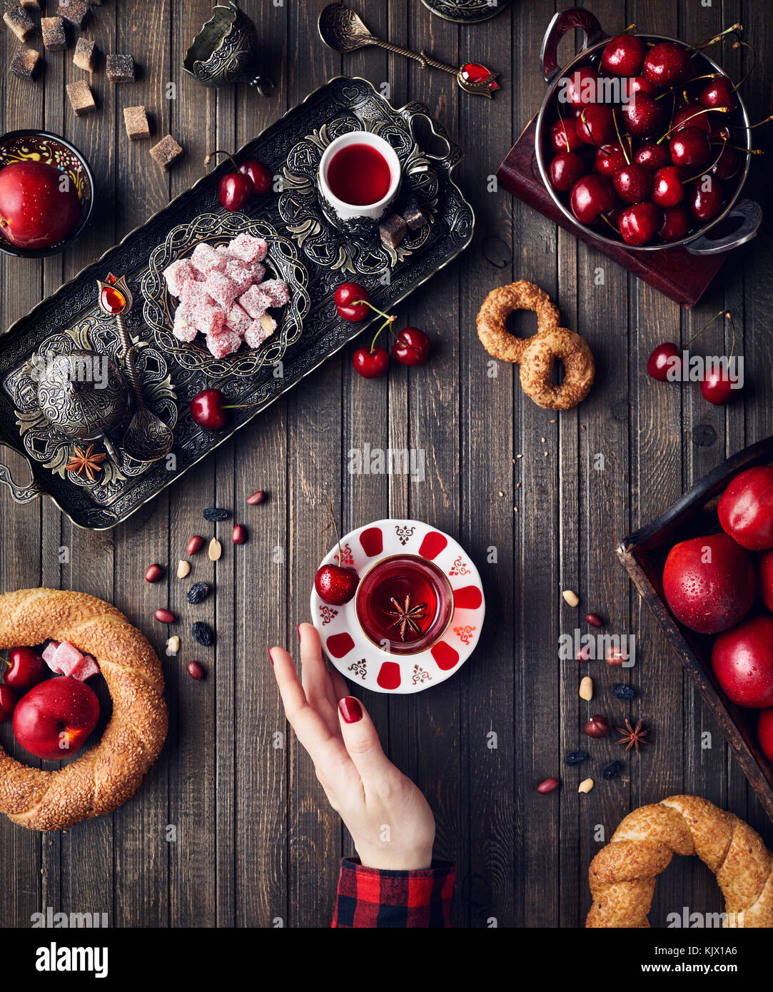 Woman touching red tea near Turkish delights rahat lokum, simits and ...