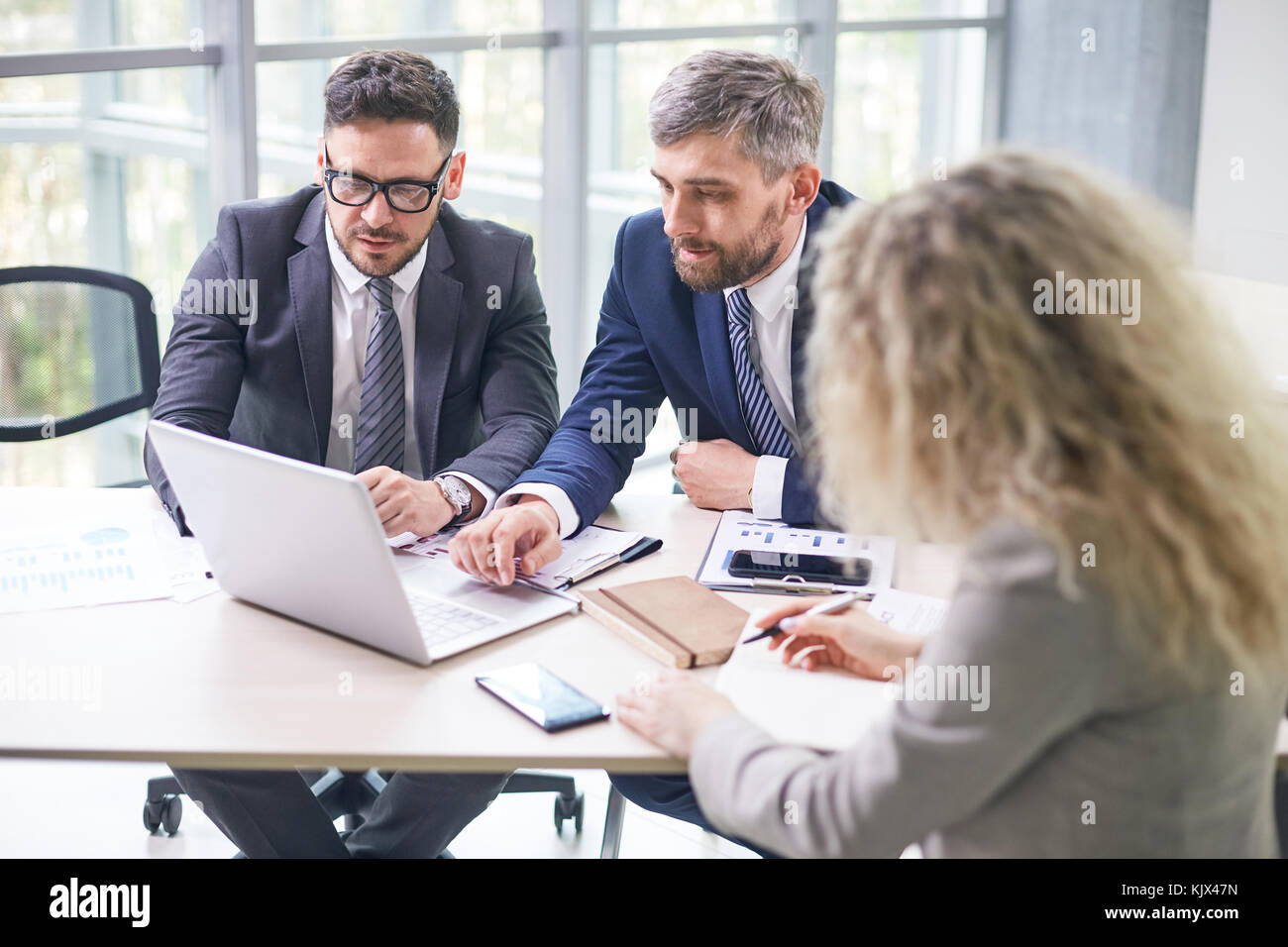 Group of concentrated financial managers sitting at spacious open plan ...