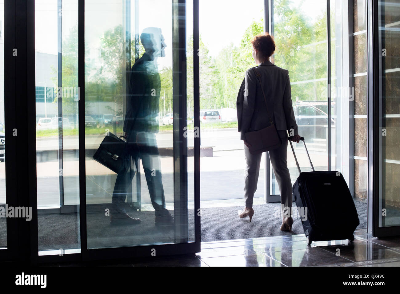 Back view silhouette of young businesswoman with suitcase walking ...