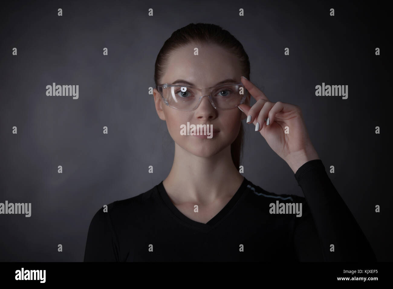 Beautiful woman with transparent futuristic glasses on dark background ...