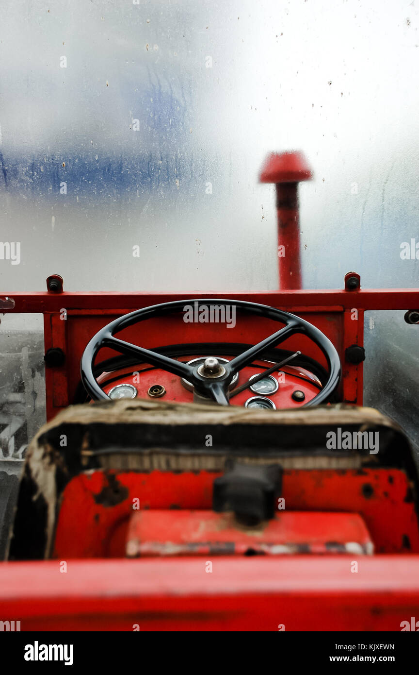 in cabin of red tractor with wheel on rainy day and steamy window Stock ...