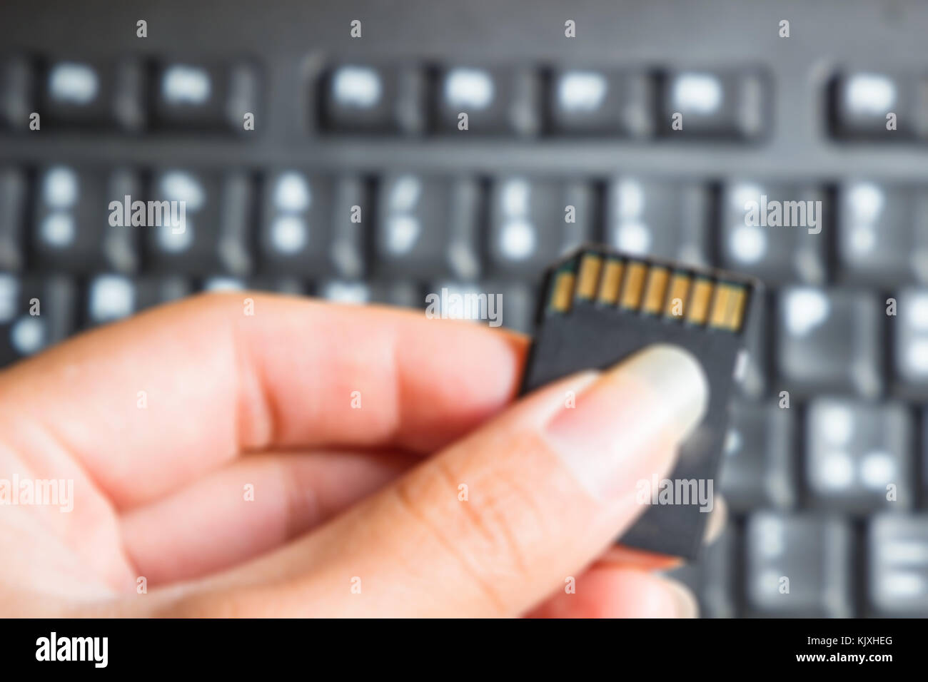 Blurred image. Hand holding a memory card over laptop keyboard ...