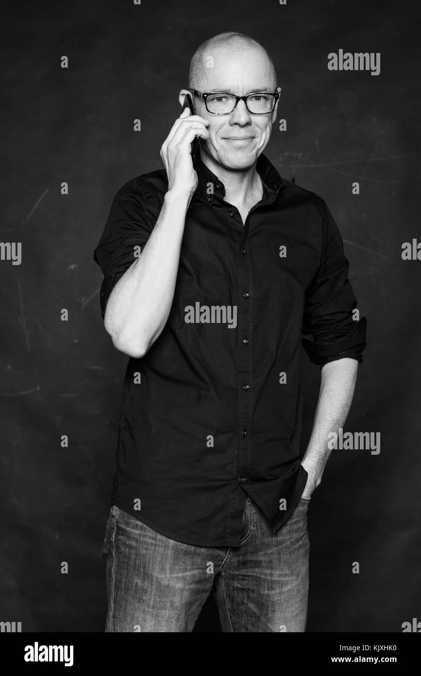 Man with cell in front of black background Stock Photo - Alamy