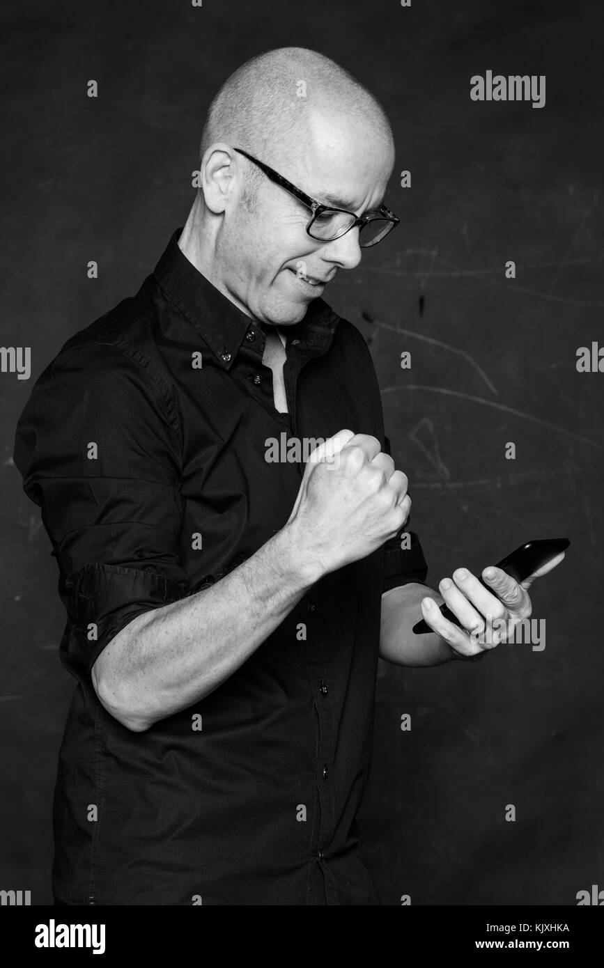 Man with cell in front of black background Stock Photo - Alamy