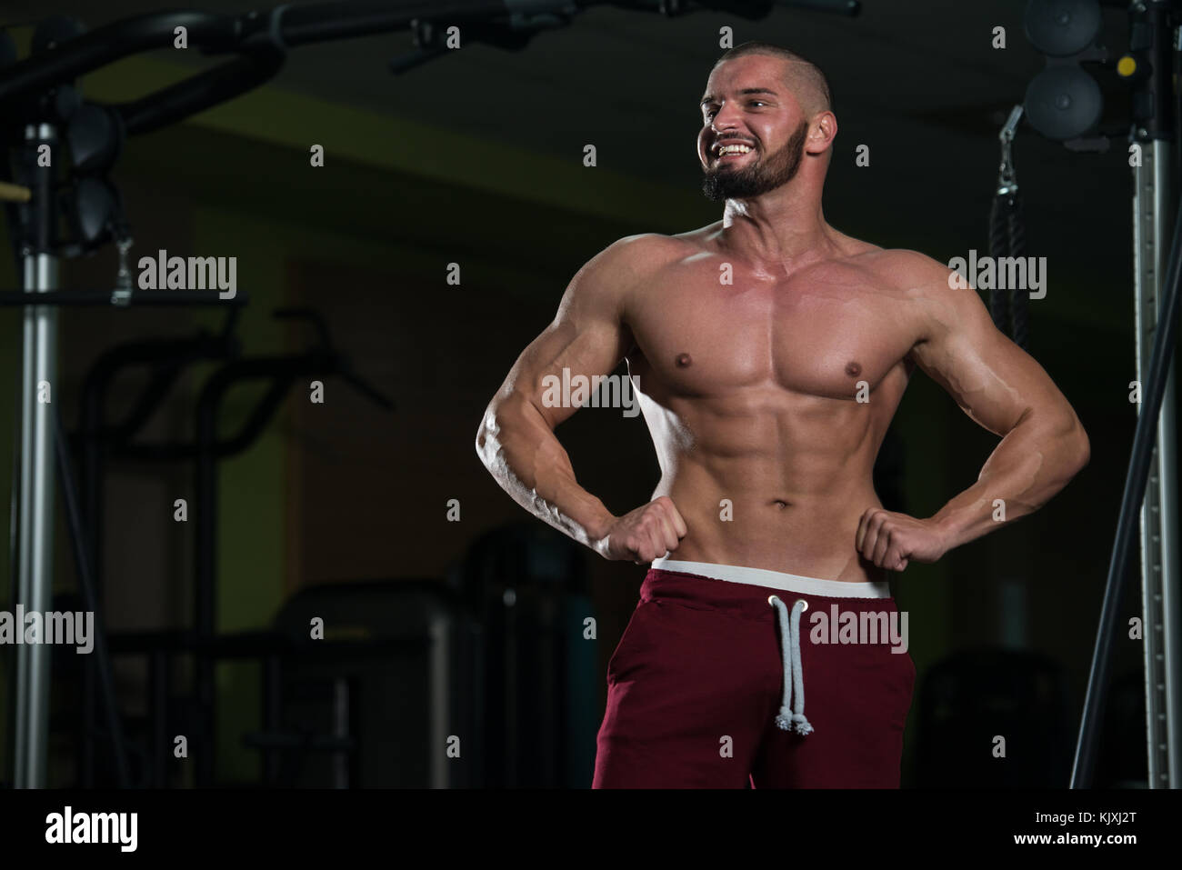 Healthy Young Man Standing Strong In The Gym And Flexing Muscles ...