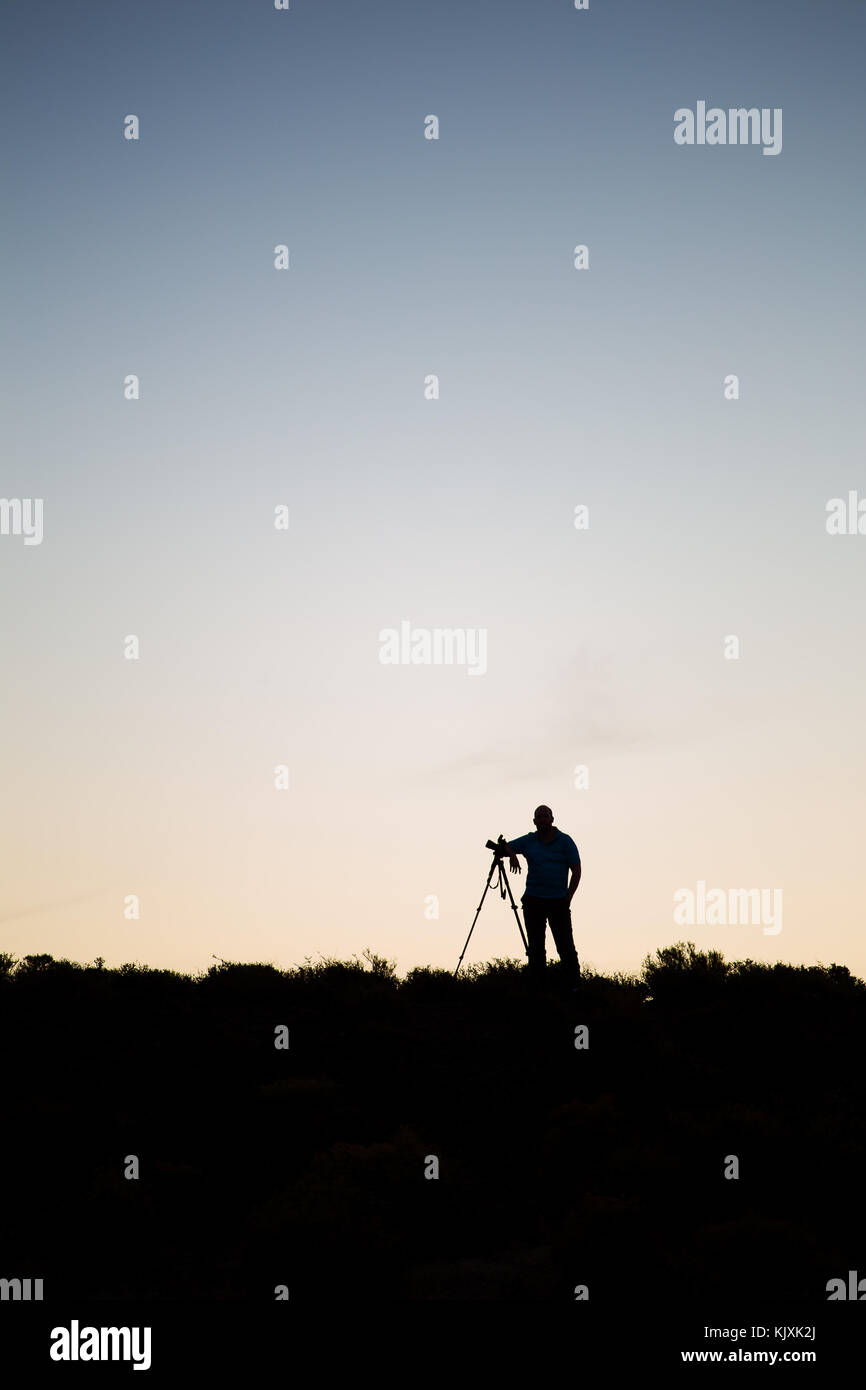 Silhouette of a photographer with his tripod on a hill with dawn ...