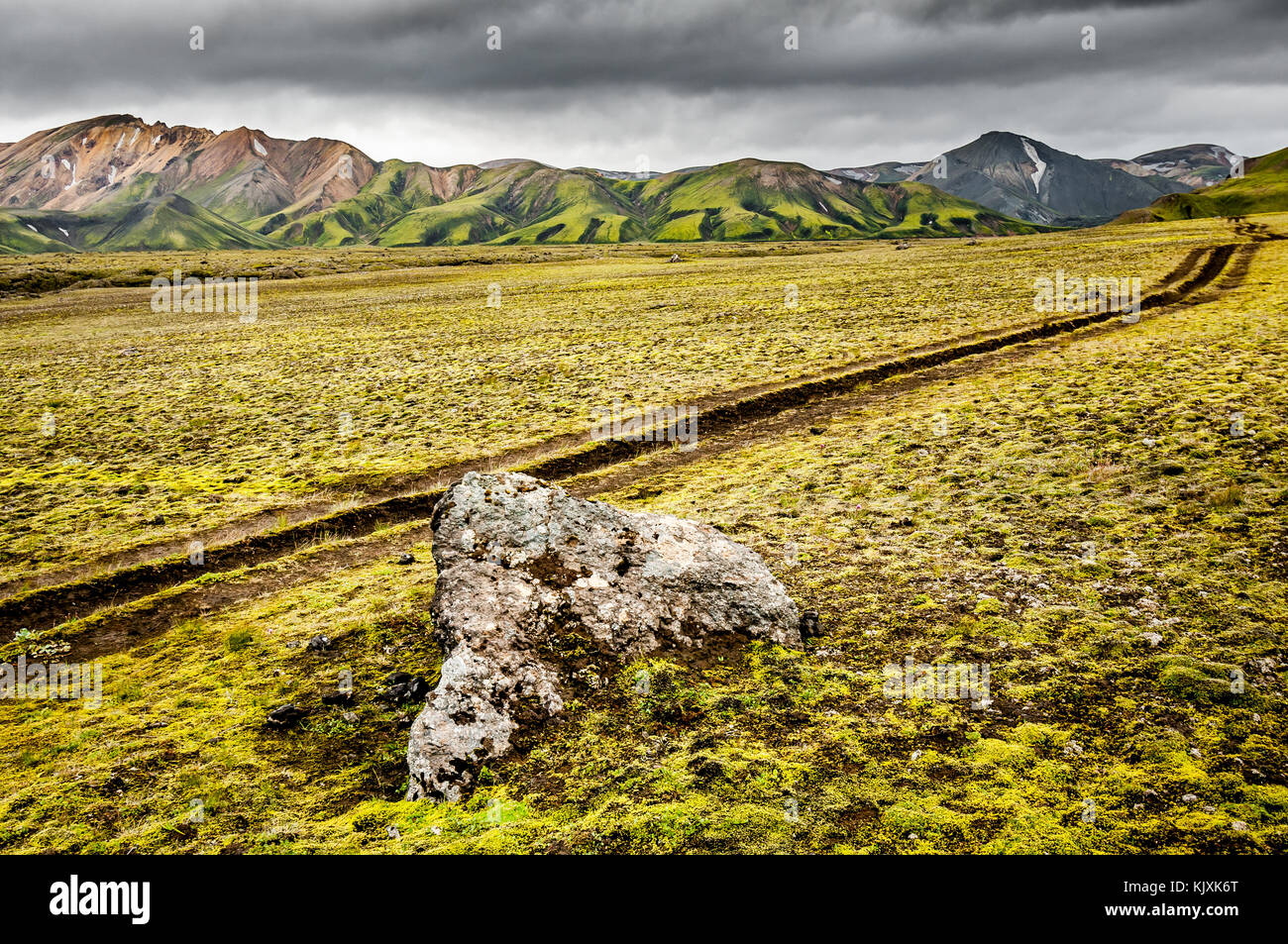 Lonely stone, path in a vast meadow and colorful mountains of the ...