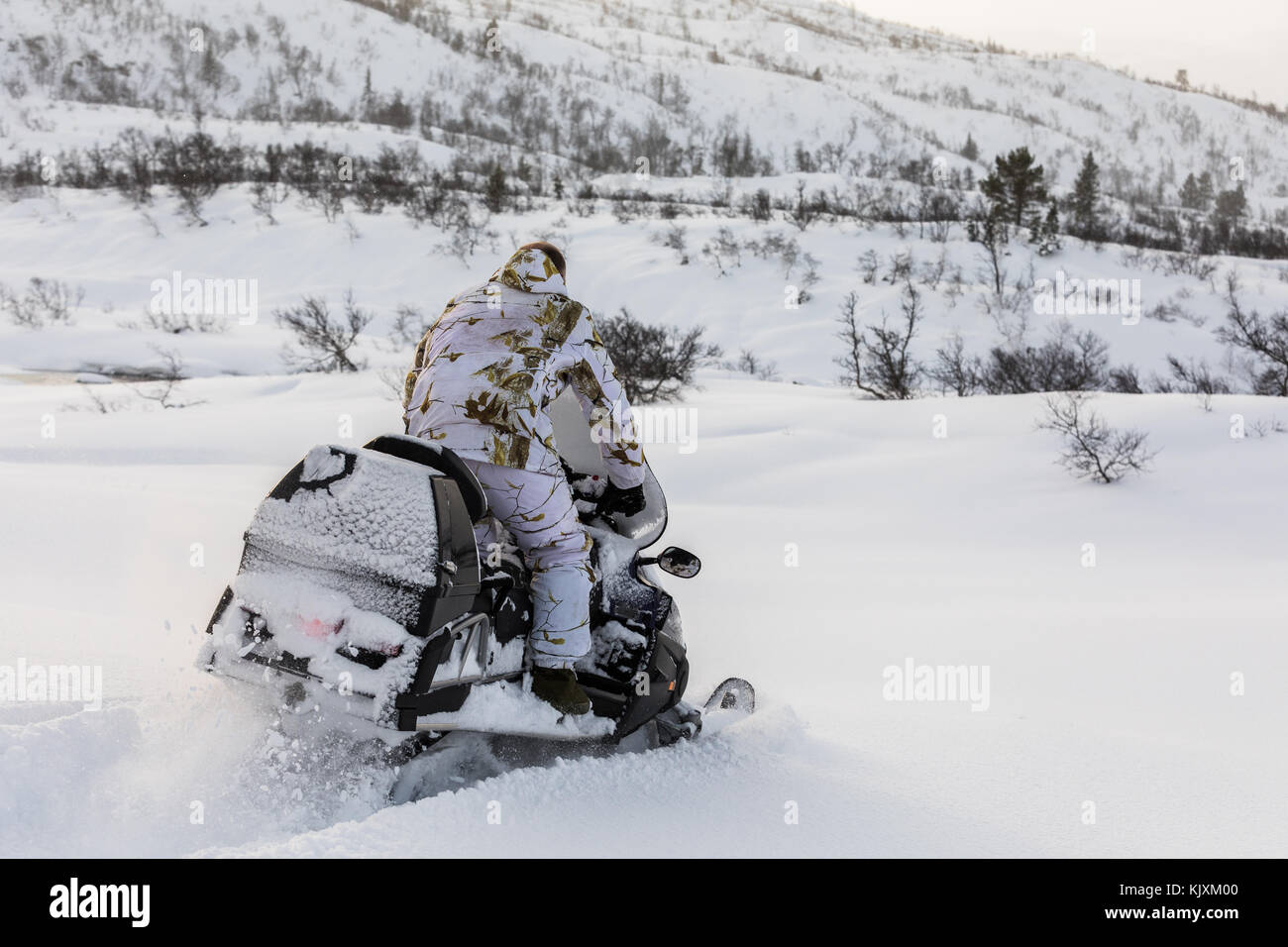 Man driving snowmobile in the snow Stock Photo - Alamy