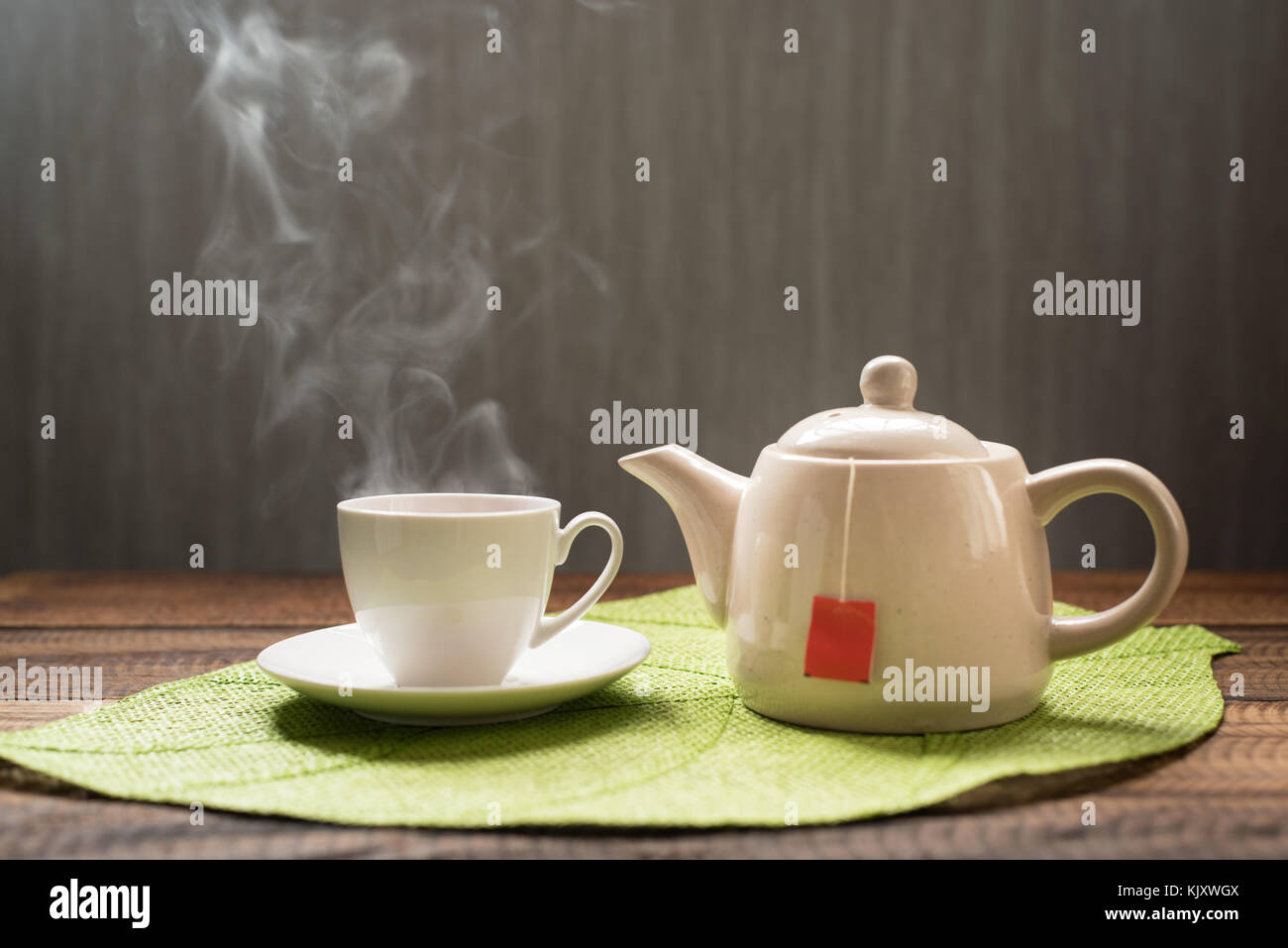 hot tea with steam and teapot on a table background. hot tea and teapot ...