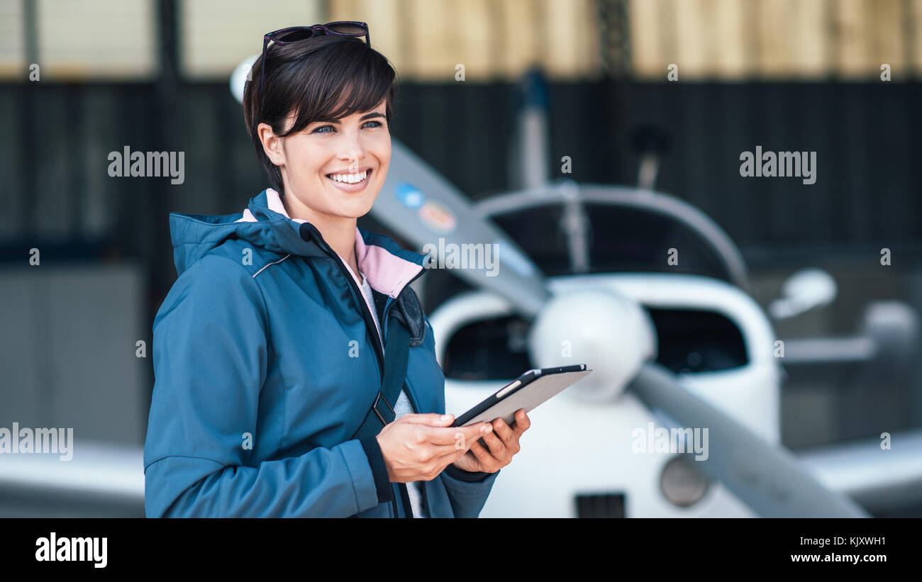 Confident female pilot in the hangar preparing before departure, she is ...