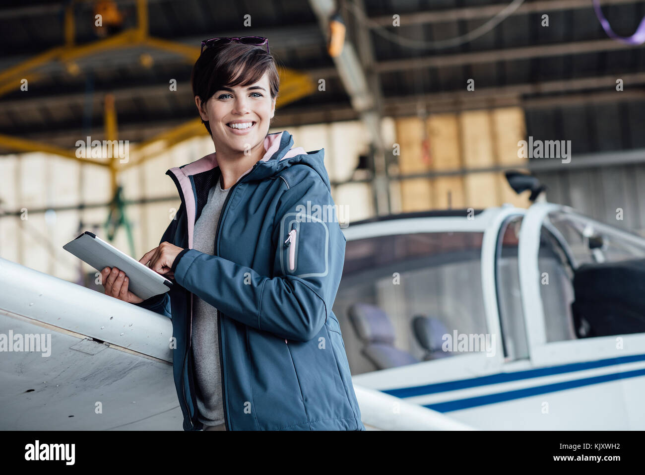 Smiling female pilot connecting with a digital tablet and using ...