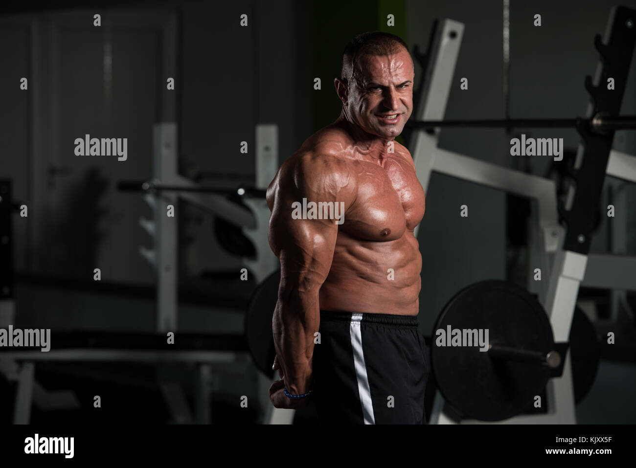 Handsome Mature Man Standing Strong In The Gym And Flexing Muscles ...