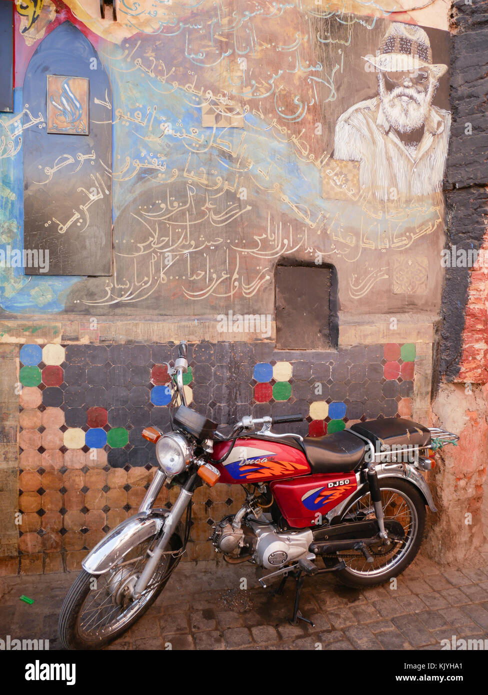 Motorcycle parked next to painted wall Stock Photo - Alamy