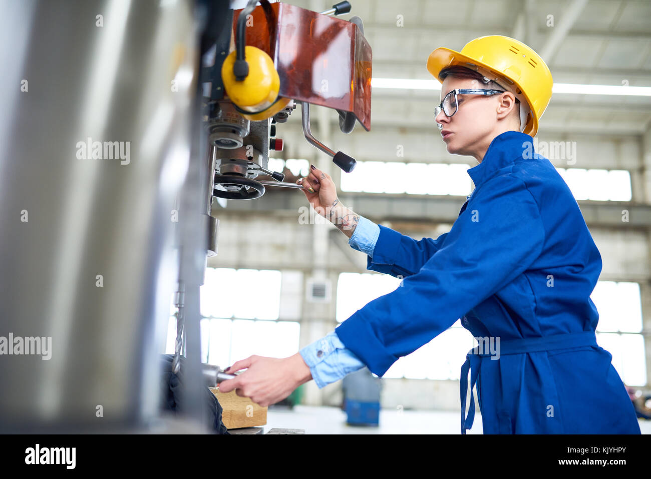 Busy experienced factory worker in hardhat focusing on work and using ...