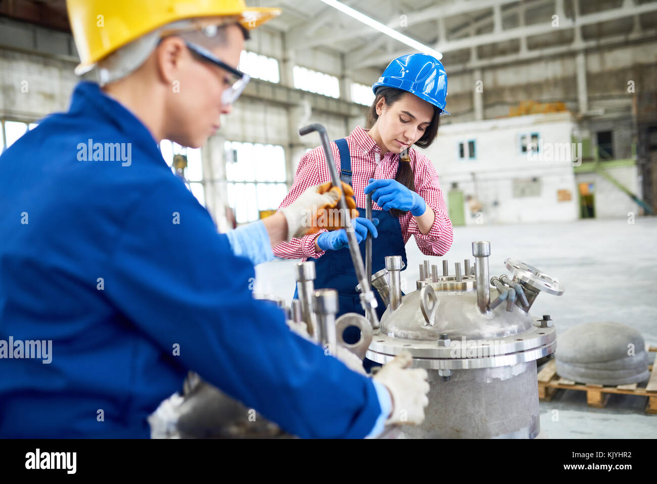 Busy young female manual workers tightening uncommon nuts while working ...