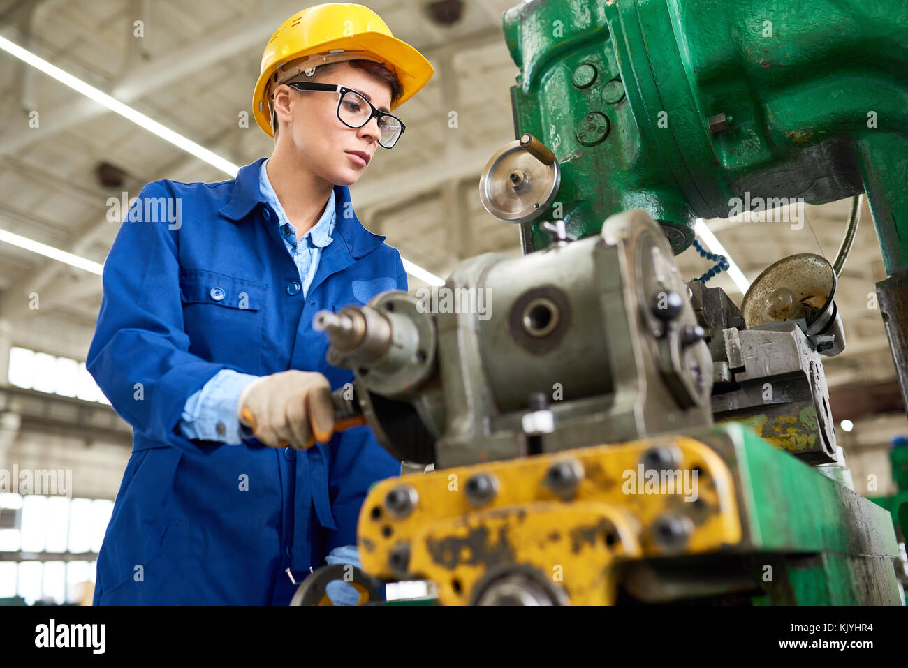 Concentrated attractive young factory operator in hardhat setting ...