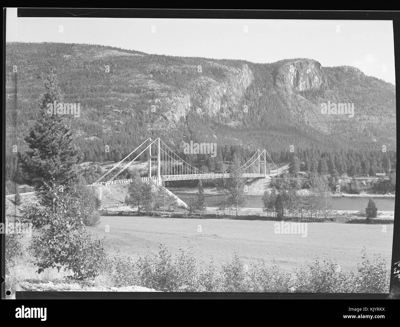 This historical photograph captures a scenic view featuring a bridge ...