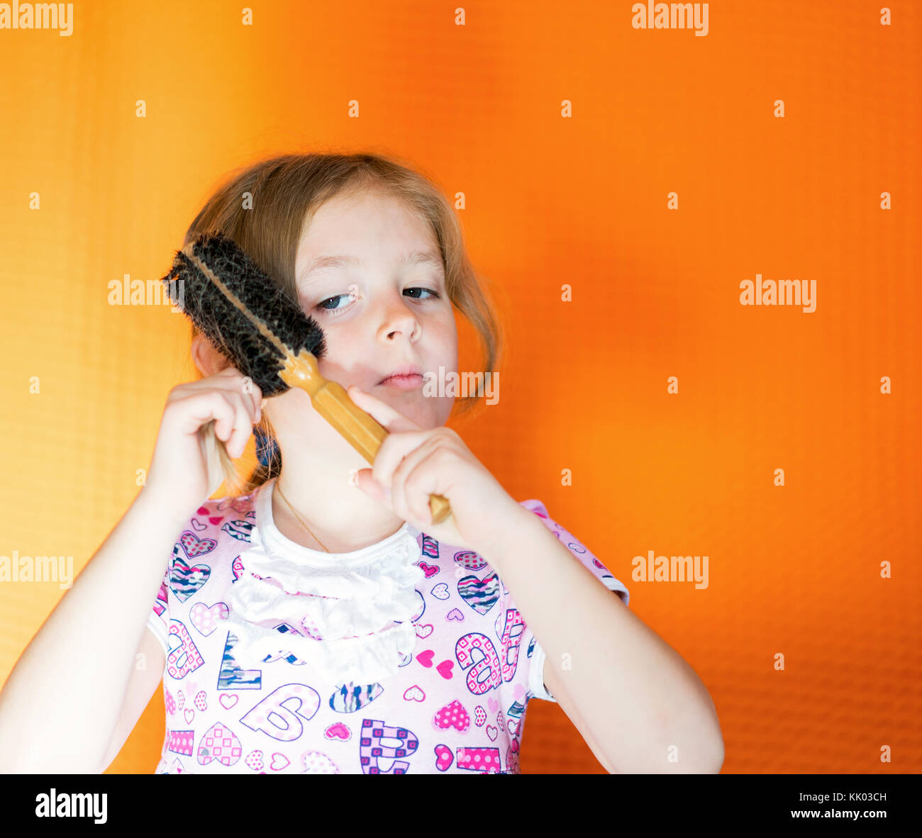 little girl with comb on orange background Stock Photo - Alamy