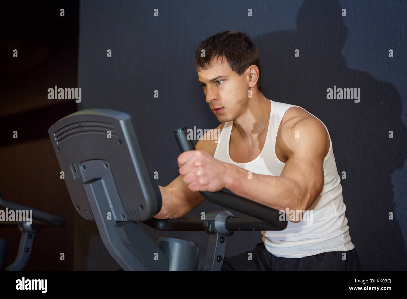 Young muscular man training on exercise bike in gym Stock Photo - Alamy