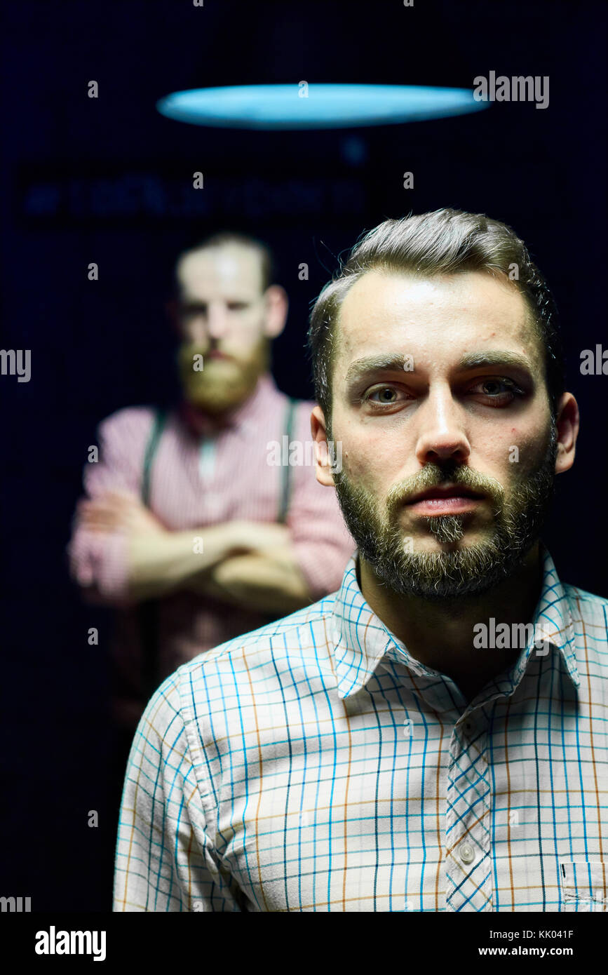 Portrait of two handsome men posing looking at camera against black ...