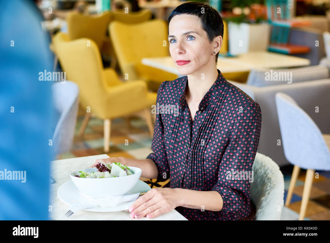 Portrait of satisfied customer sitting at table in cafe with salad bowl ...
