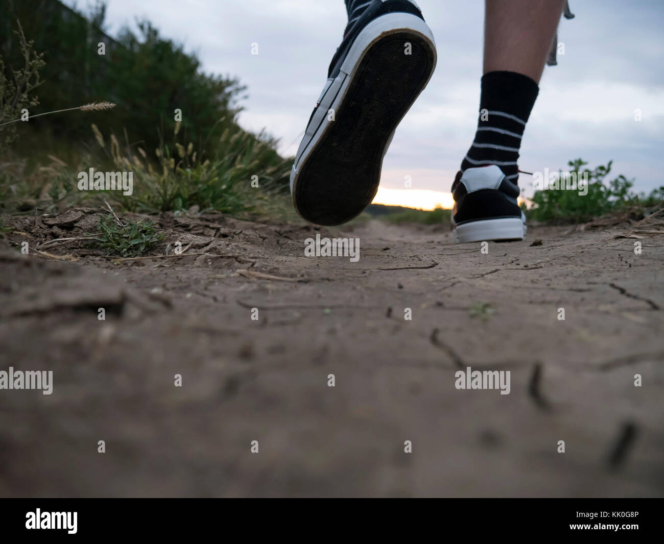 Man feet walking on dry dirt path in sunset and cloudy weather Stock ...